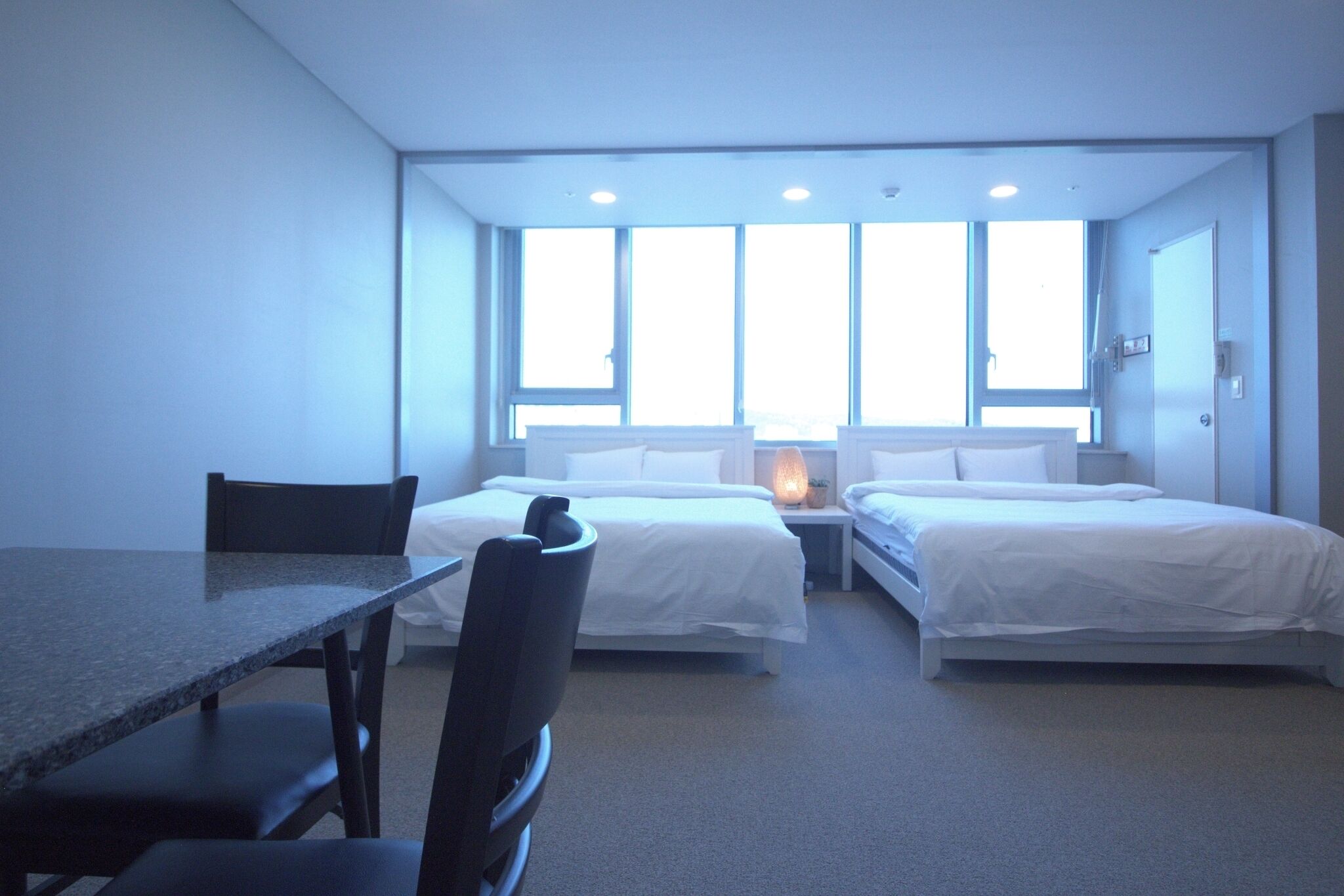Quarto de hotel com duas camas, uma escrivaninha e uma cadeira.