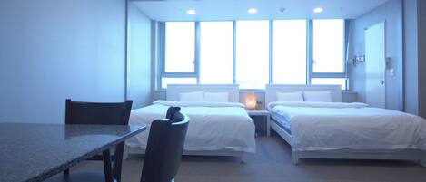 Quarto de hotel com duas camas, uma escrivaninha e uma cadeira.