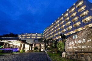 Um hotel com vários andares, uma entrada bem iluminada e uma grande placa com o nome do hotel.