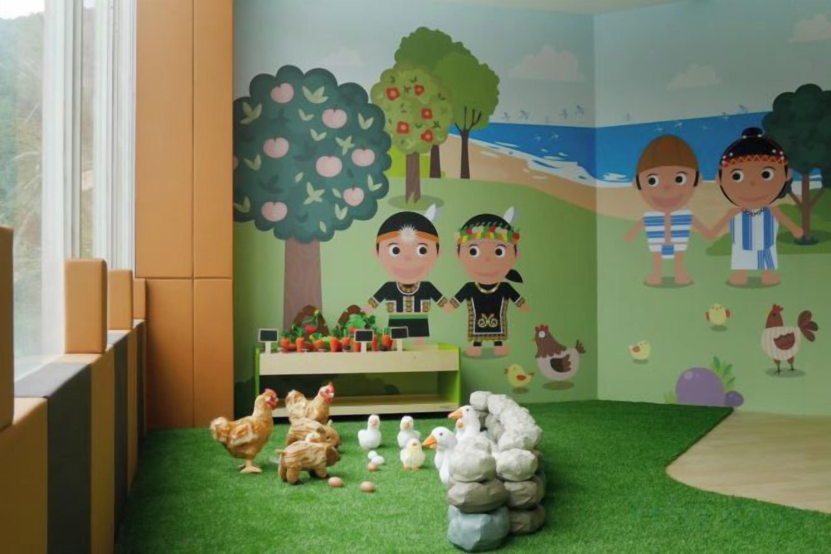Uma sala de brinquedos infantil com um mural, grama sintética e bichos de pelúcia.