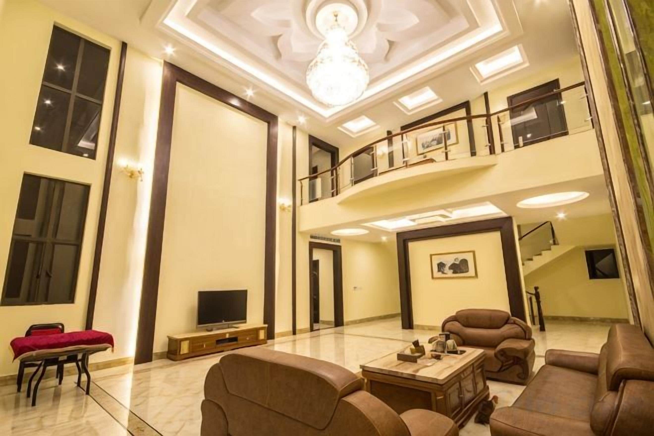 Uma sala de estar ampla com televisão de tela plana, sofás de couro e um candelabro.
