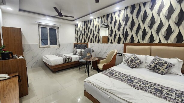 Quarto de hotel com duas camas, uma escrivaninha, uma cadeira, um ventilador de teto e uma janela.