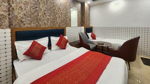Quarto de hotel com duas camas, uma mesa de jantar e um ventilador de teto.