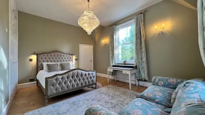 Quarto com cama grande, escrivaninha e janela com cortinas.