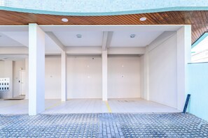 Um espaço interno vazio com piso de azulejos, paredes brancas e teto de madeira.