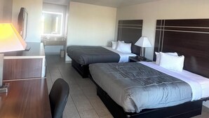 Quarto de hotel com duas camas, uma escrivaninha e uma cadeira.