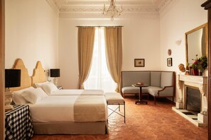 Quarto de hotel com duas camas, lareira, área de estar e um espelho grande.