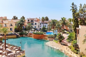 Resort com piscina, palmeiras e vários edifícios.