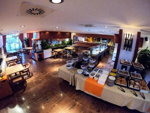 Uma área de buffet com diversos tipos de comida e um espaço de refeições com mesas e cadeiras.