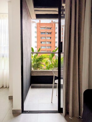 Uma varanda com vista para um prédio de tijolos e vegetação.