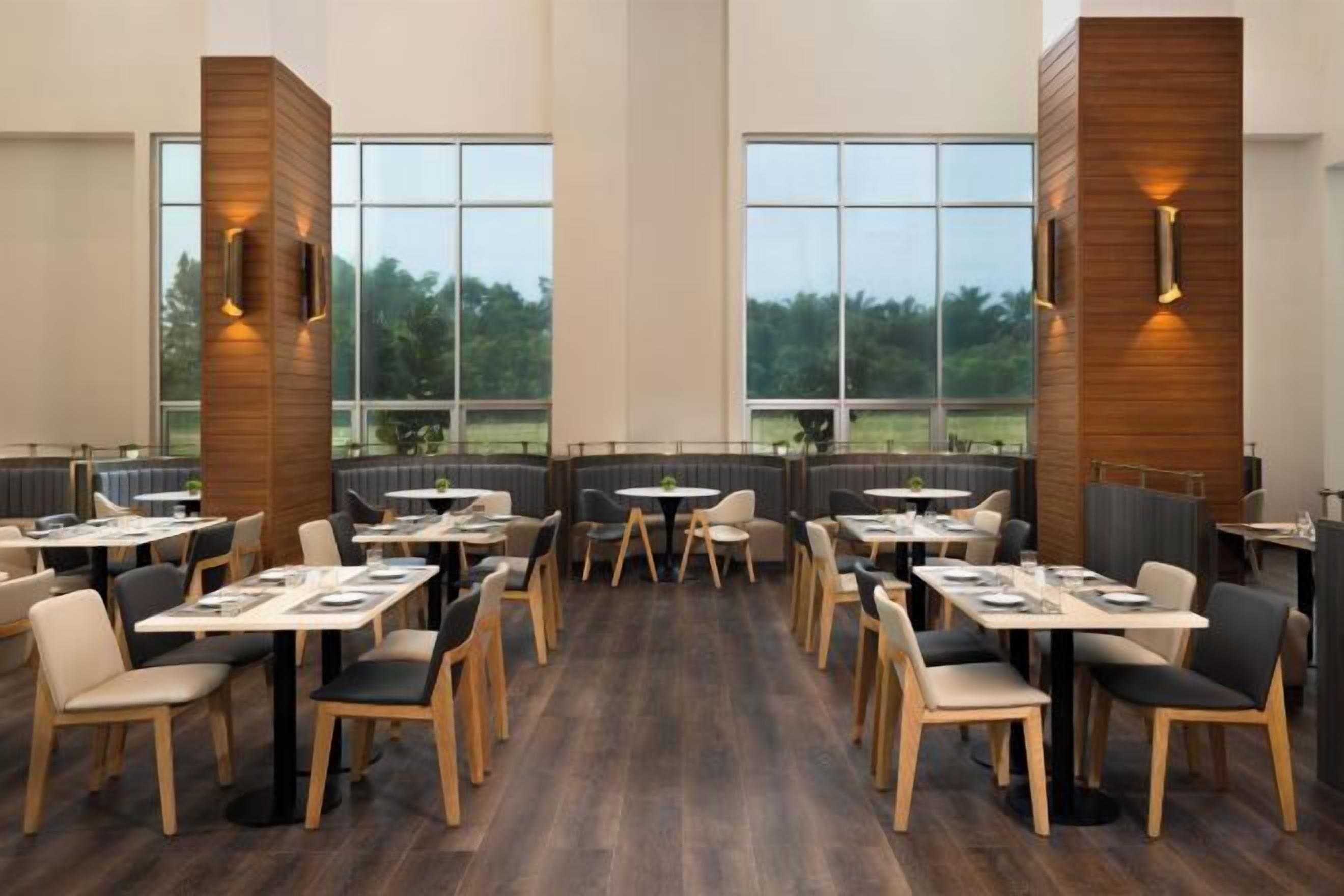 Restaurante com pé direito alto, grandes janelas e design de interiores moderno.