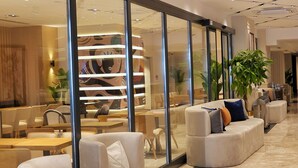 Um lobby moderno com uma extensa área de estar, grandes janelas e uma instalação artística central.