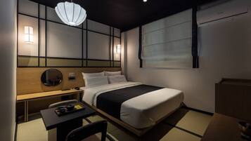 Quarto de hotel moderno com cama, mesa de cabeceira e escrivaninha com cadeira.