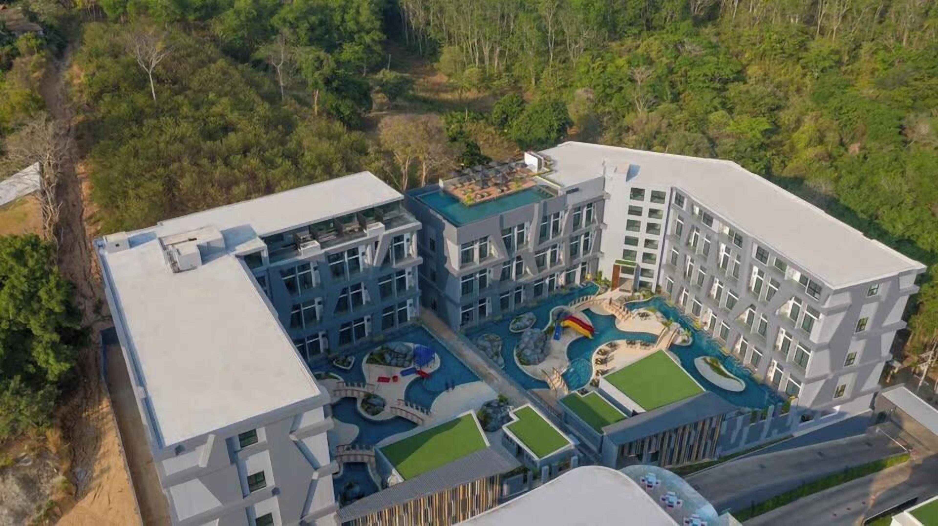Um hotel moderno com vários andares, piscina no terraço e jardins bem cuidados.