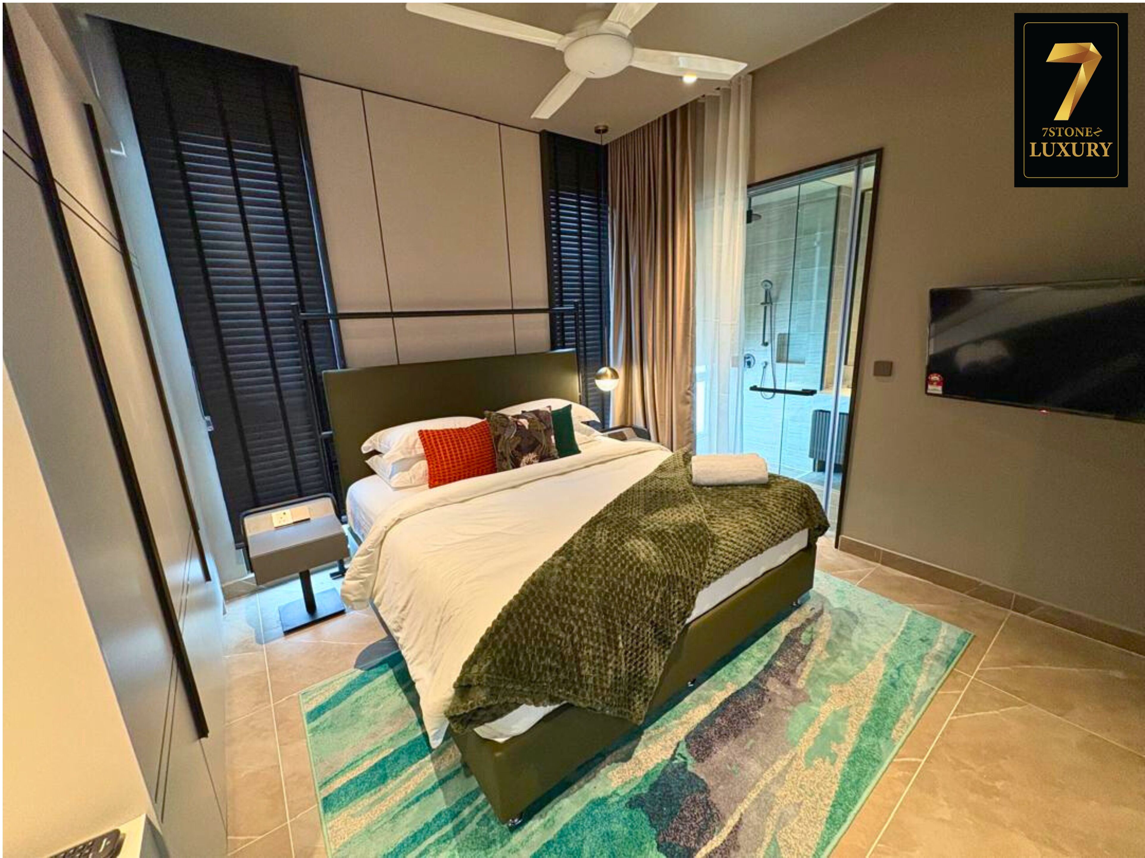 Quarto moderno com cama, TV e porta de vidro deslizante que dá para uma área de chuveiro.