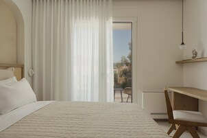 Quarto com cama, cadeira, escrivaninha e vista para o exterior.