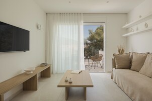 Uma sala de estar moderna com um sofá, uma mesa de centro, uma televisão e um banco.