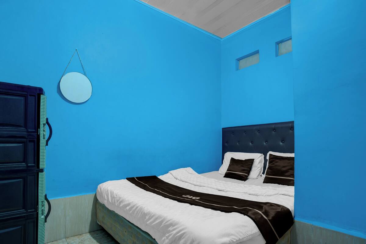 Quarto com cama, espelho redondo e guarda-roupa.