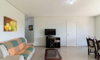 Uma sala de estar com sofá, mesa de centro, rack para TV e uma porta.