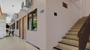 Um corredor com escadas, aparelhos de ar condicionado e uma porta com uma placa.