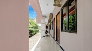 Um corredor com piso ladrilhado, janelas amplas e aparelhos de ar condicionado.