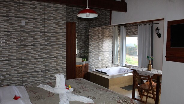 Quarto de hotel com cama, banheiro, área de refeições e vista para o exterior.