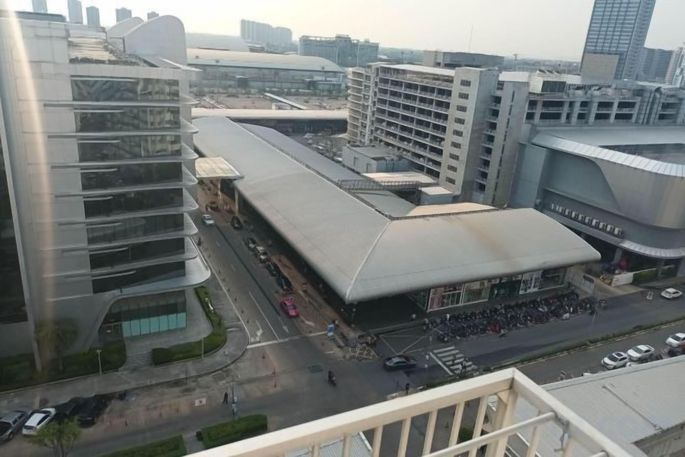 Um edifício moderno com telhado curvo e amplo espaço aberto à frente.