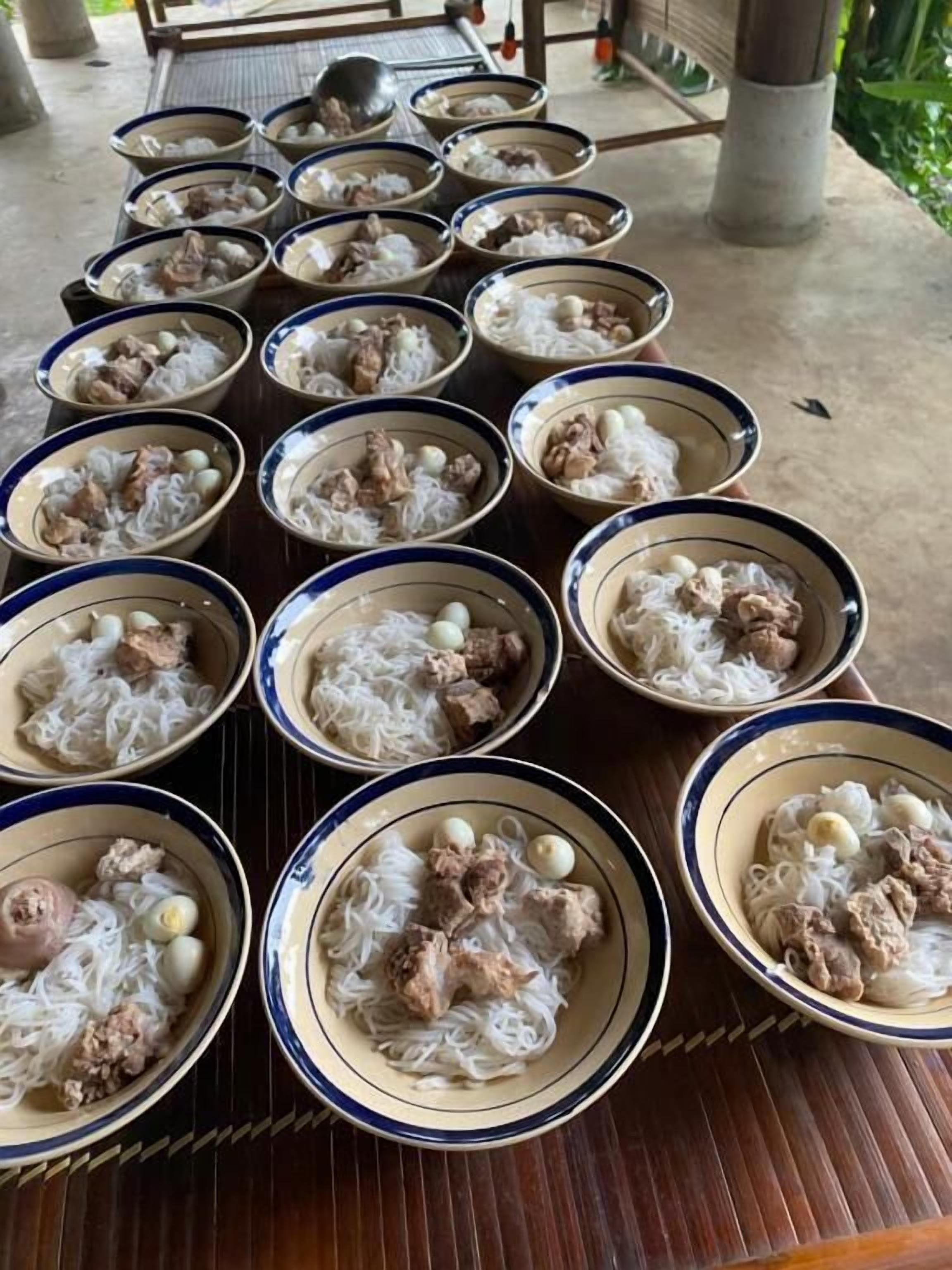 Vários tigelas de sopa de macarrão com carne e ovos cozidos sobre esteira de bambu.