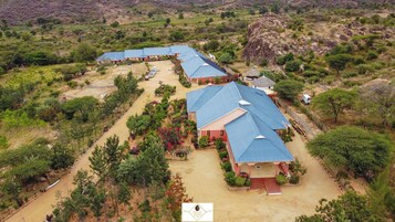 Um hotel com vários edifícios, cada um com telhado azul, rodeado por vegetação e uma paisagem montanhosa.