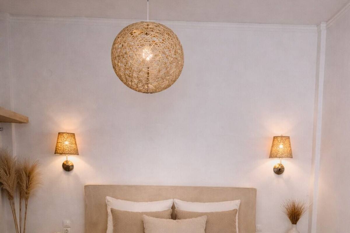 Quarto com uma cama grande, duas luminárias de cabeceira, uma luminária de teto de tecido e um tapete texturizado.