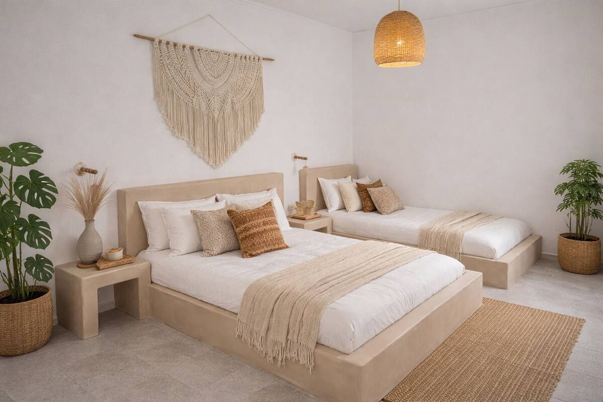 Quarto com duas camas, um painel de macramé, luminária pendente de fibra e plantas em vasos.