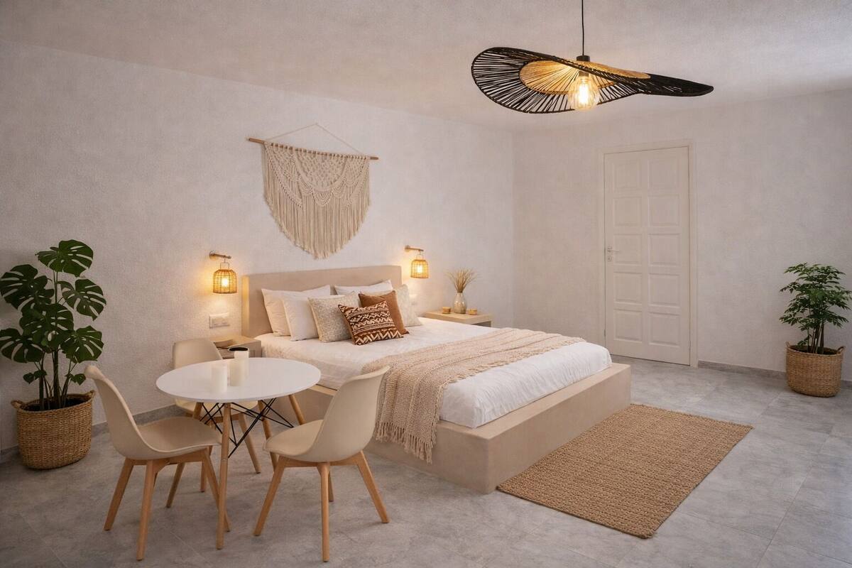 Quarto com cama, mesas de cabeceira, decoração de parede em macramé, mesa redonda com cadeiras e duas plantas em vasos.