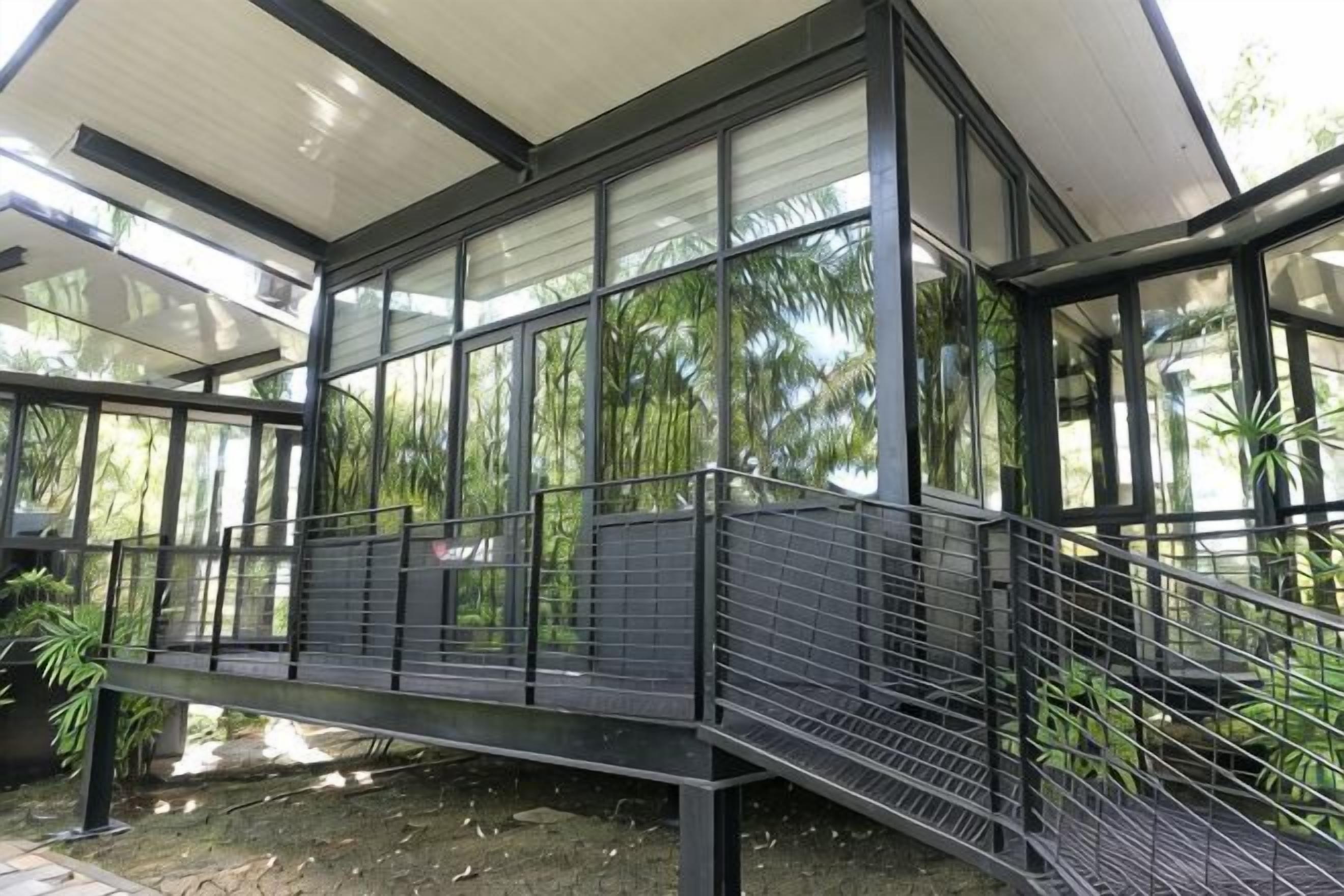 Um edifício moderno com grandes janelas, escada de metal e área externa coberta.