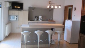 Uma cafeteira/bule, um frigorífico, um micro-ondas 