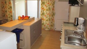 Uma cafeteira/bule, um frigorífico, um micro-ondas 