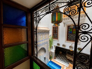 Um quarto com vista através de uma janela com vitrais, parede estampada e chão de azulejos.