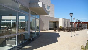 Um edifício moderno com amplas janelas de vidro, área de estar ao ar livre e céu claro.