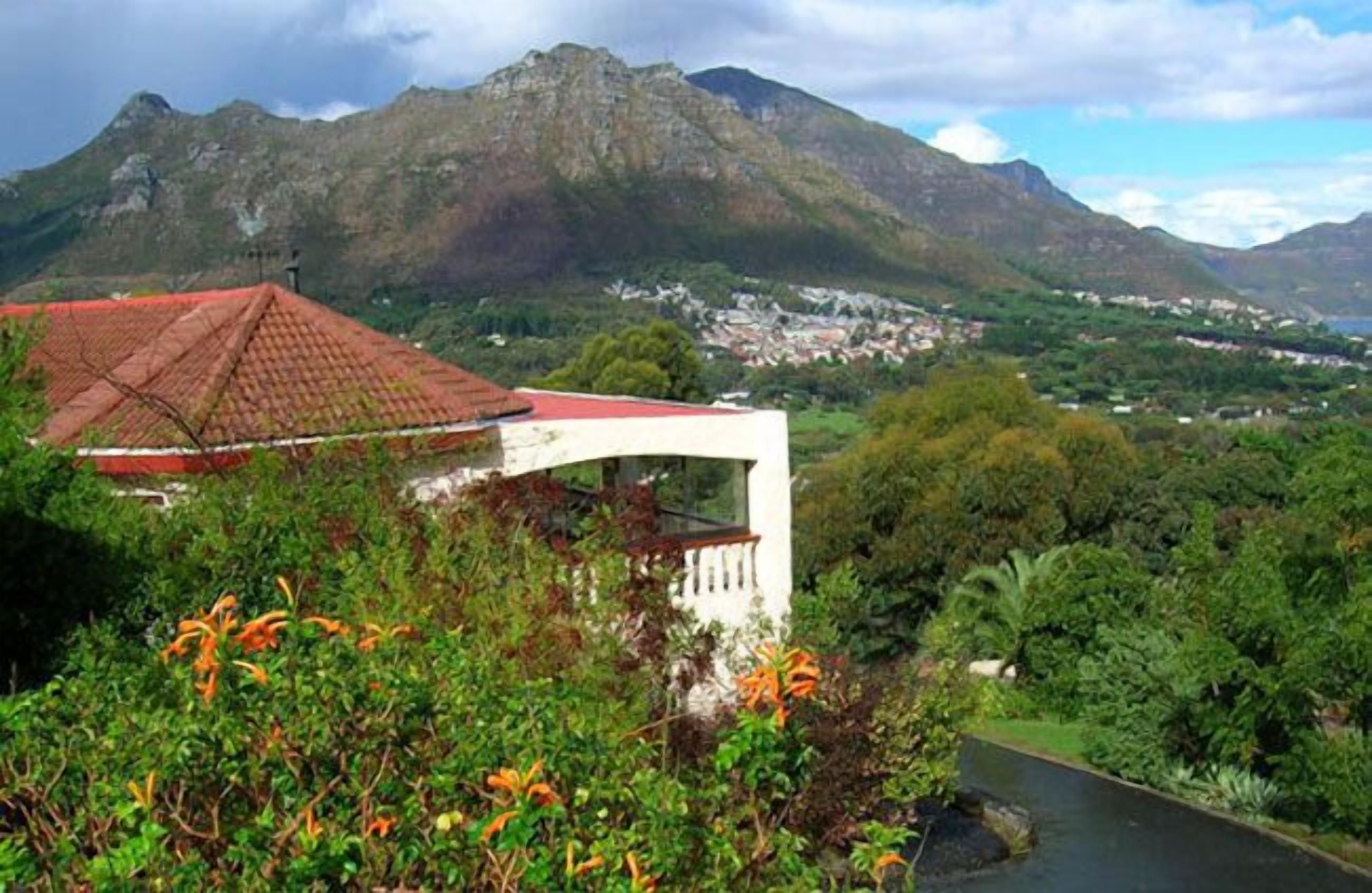 Paisagem montanhosa com um edifício de telhado vermelho e um rio em primeiro plano.