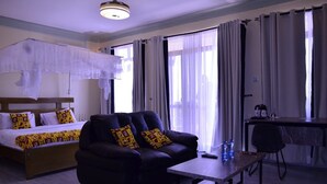 Quarto de hotel com cama, sofá, escrivaninha e cadeira.