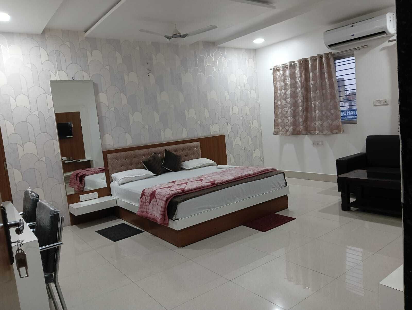 Quarto com cama, espelho, escrivaninha e aparelho de ar condicionado.