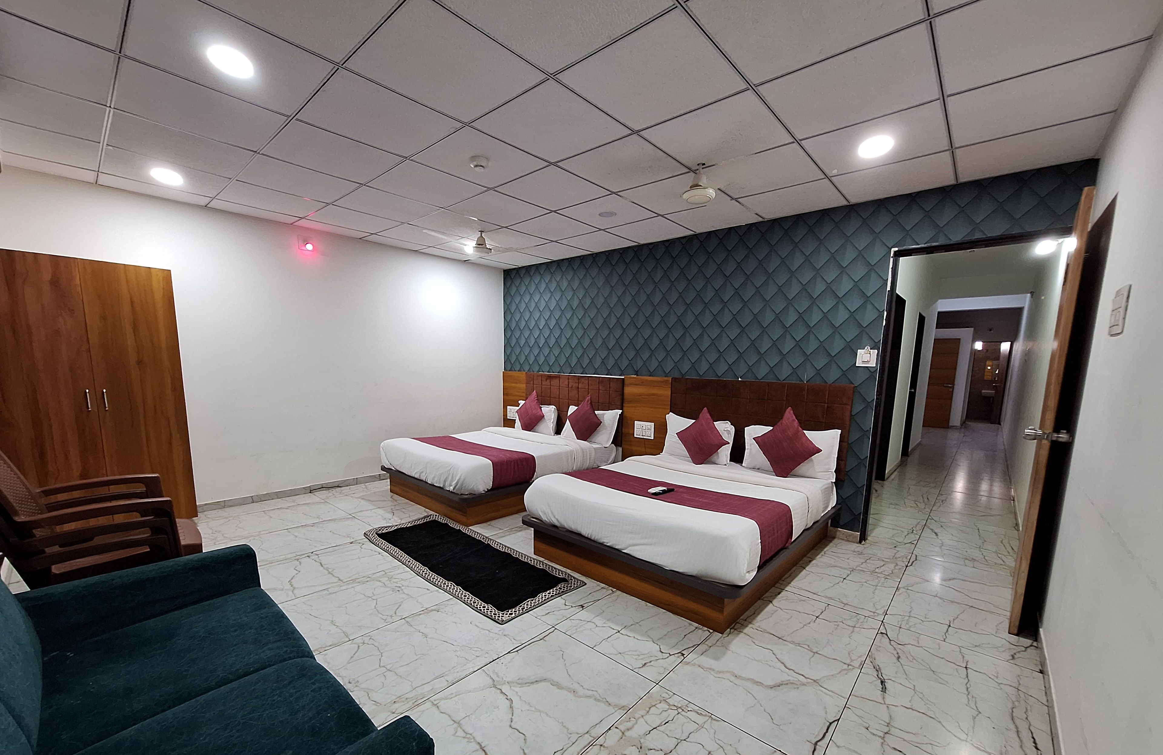 Quarto de hotel com duas camas, um guarda-roupa, um espaço de estar e um corredor.