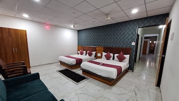 Quarto de hotel com duas camas, um guarda-roupa, um espaço de estar e um corredor.