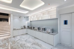 Uma cozinha moderna com piso de mármore, armários brancos e prateleiras embutidas.