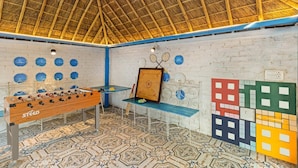 Um quarto com mesa de pebolim, mesa de ping pong e mesa para jogos de tabuleiro.