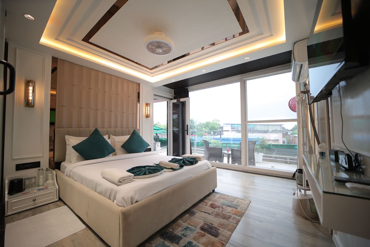 Quarto de hotel moderno com uma cama grande, televisão de tela plana e varanda com vista para a cidade.