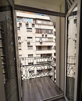 Uma varanda com guarda-corpo de metal e vista para um edifício de vários andares com varandas.