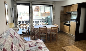 Uma sala de estar acolhedora com sofá, mesa de jantar com cadeiras e cozinha com armários de madeira e fogão.