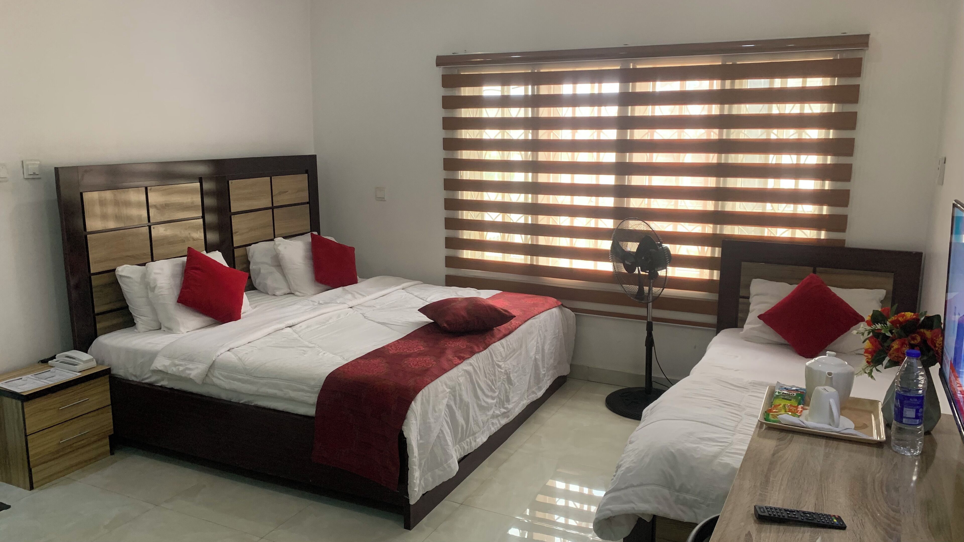 Quarto de hotel com cama, mesa de cabeceira e escrivaninha com cadeira.