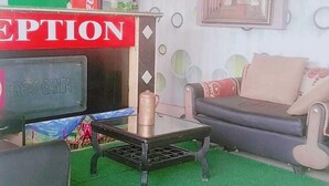 Uma sala de estar com sofá, mesa de centro, televisão e ventoinha no teto.