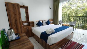 Quarto de hotel moderno com cama de madeira, varanda com vista para áreas verdes e um pequeno espaço de estar.